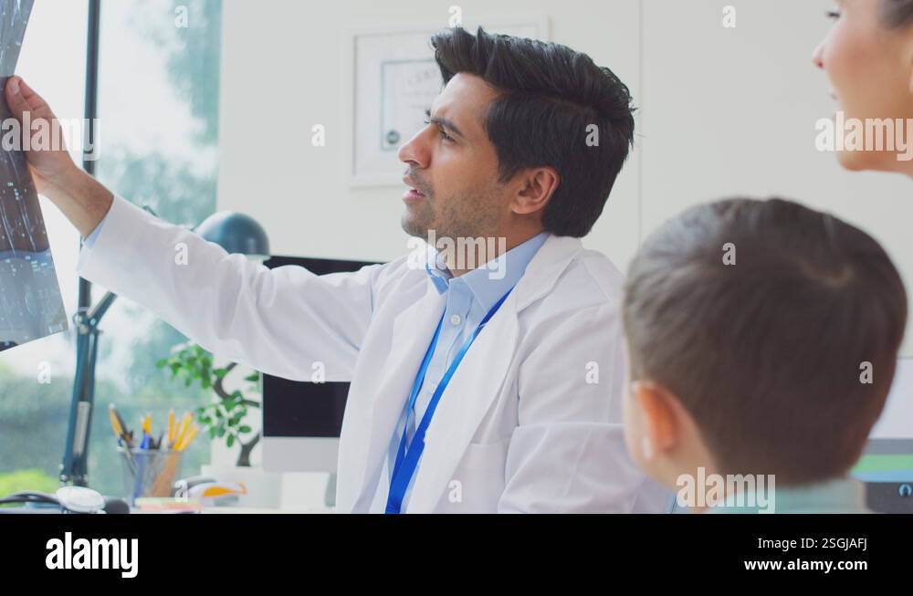 Doctor In White Coat With Mother And Son In Office Looking At MRI Or CT ...