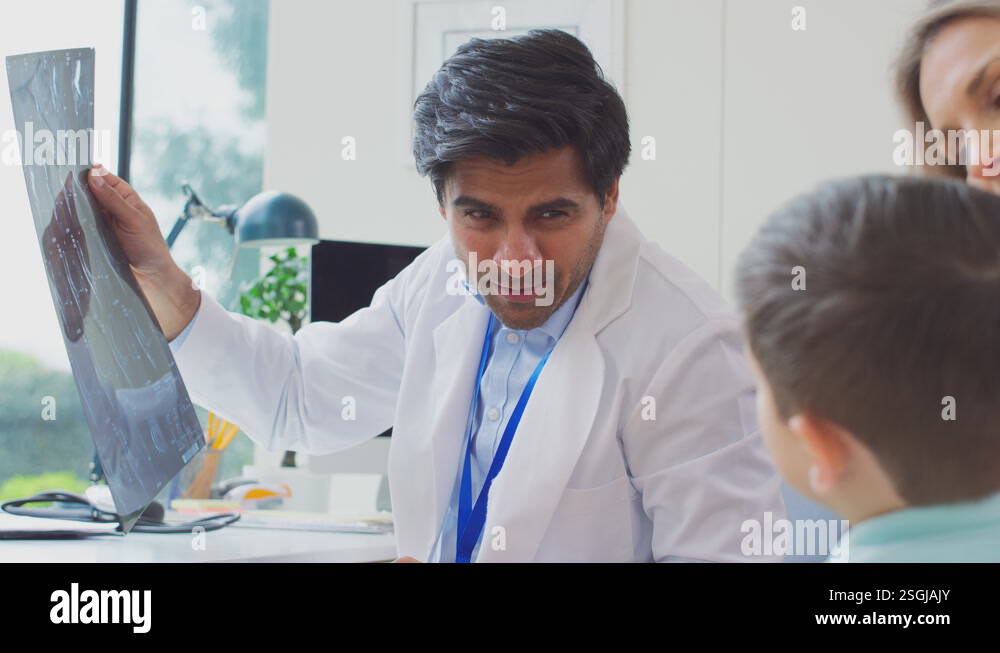 Doctor In White Coat With Mother And Son In Office Looking At MRI Or CT ...