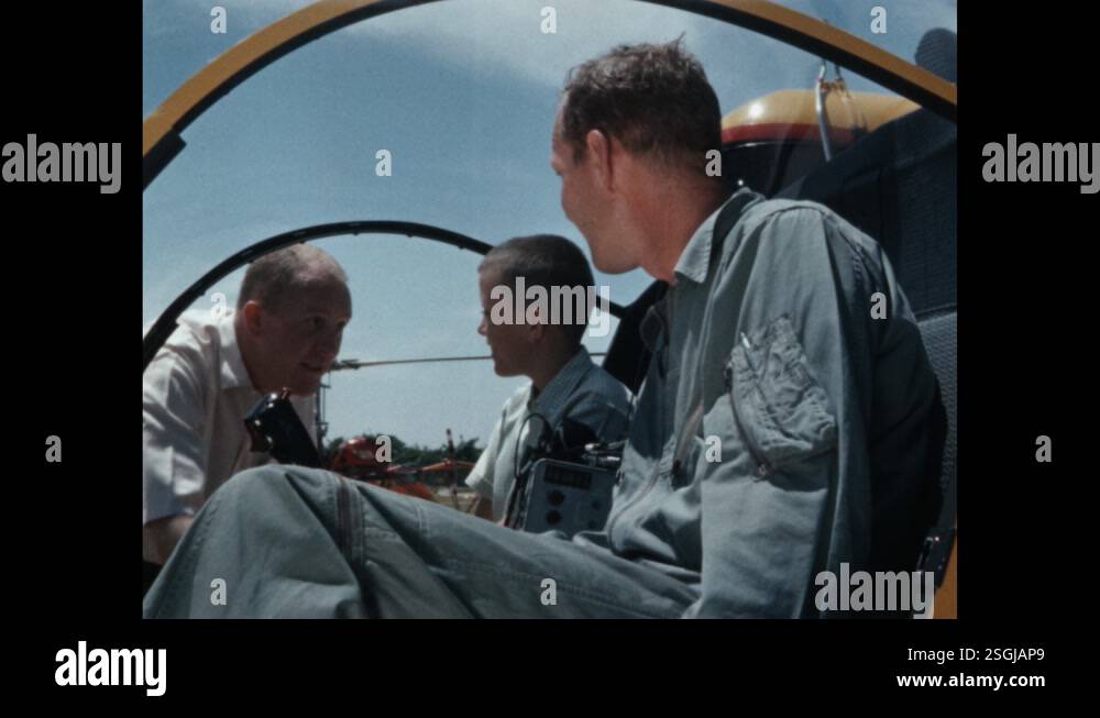 1960s: Man talking with boy and pilot sitting in cockpit. Pilot fastens ...