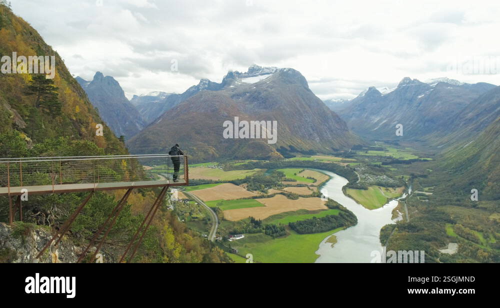 Norwegian on viewpoint platform looking at scenic nordic mountain ...