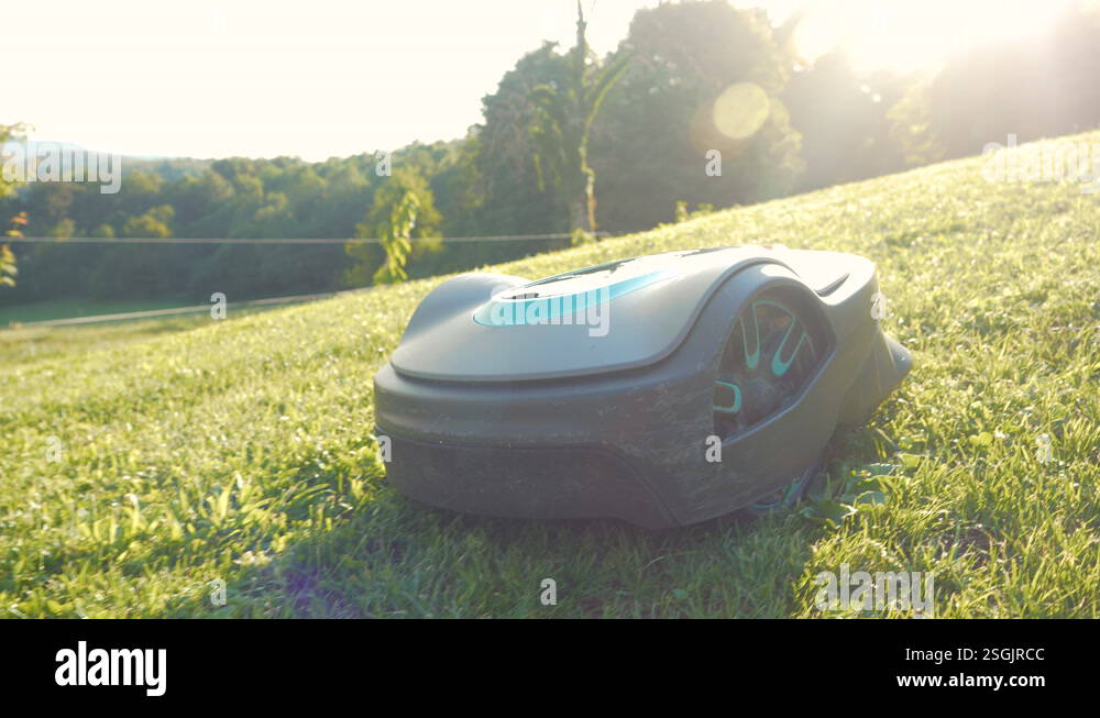 CLOSE UP: Autonomous lawn mower moving downhill and trimming grass in ...