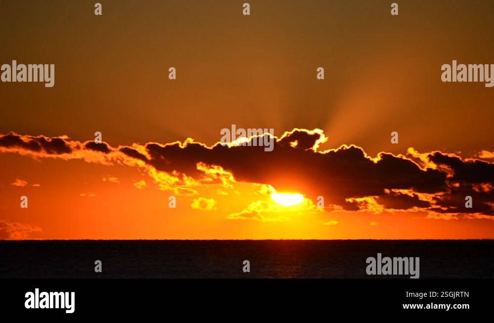Timelapse. The dawn sun go behind a cloud over the sea horizon during ...