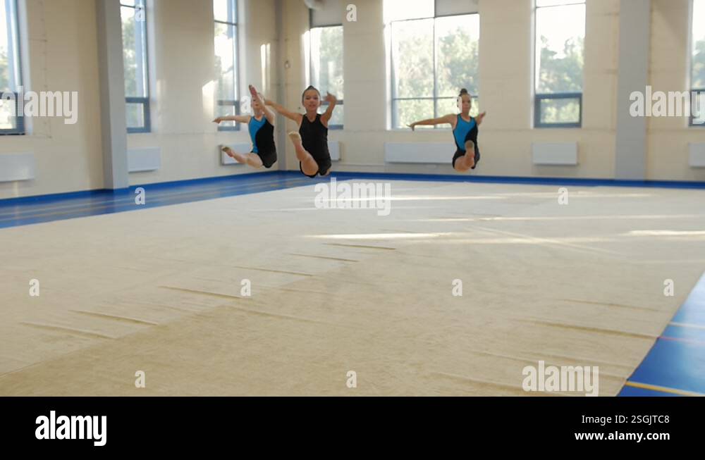 Three gymnast girls show an exercise in the gym - run to the camera and ...