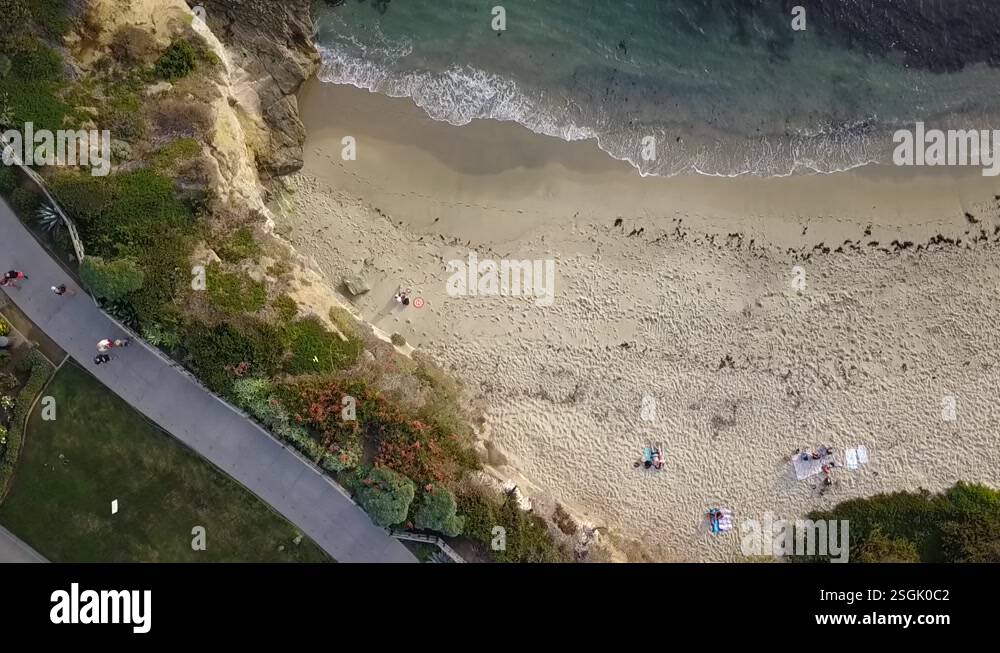a footpath with people walking at the beach surrounded by ocean water ...
