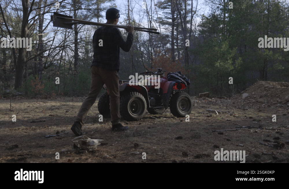 Man walking with tools towards ATV 4 wheeler in autmn fall forest ...