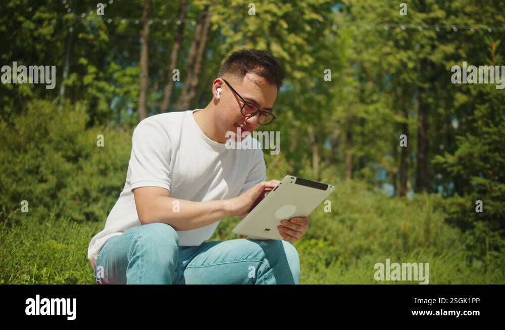 Asian man using gadget tablet outdoor close-up. Korean young guy ...
