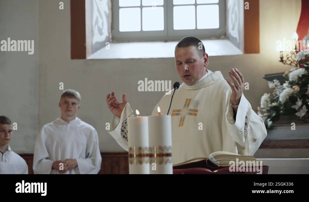 Priest raised hands up and reads prayer into microphone on altar of ...