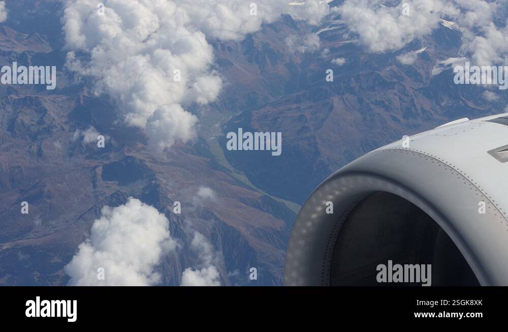 View of rugged peaks of the Alps from window of airplane. Turbine ...