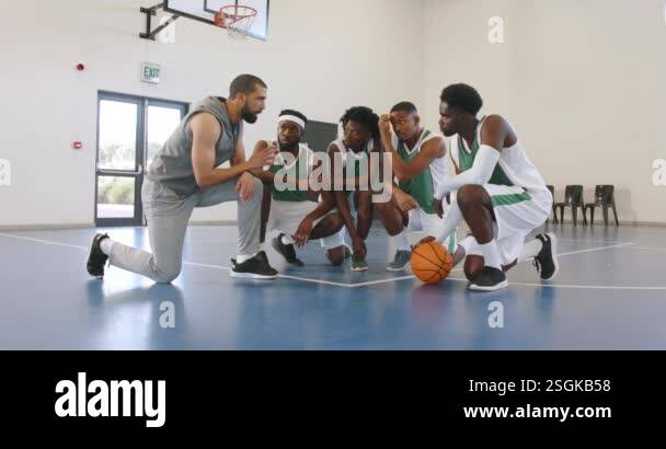 Multiracial male basketball players listening to multiracial male coach ...