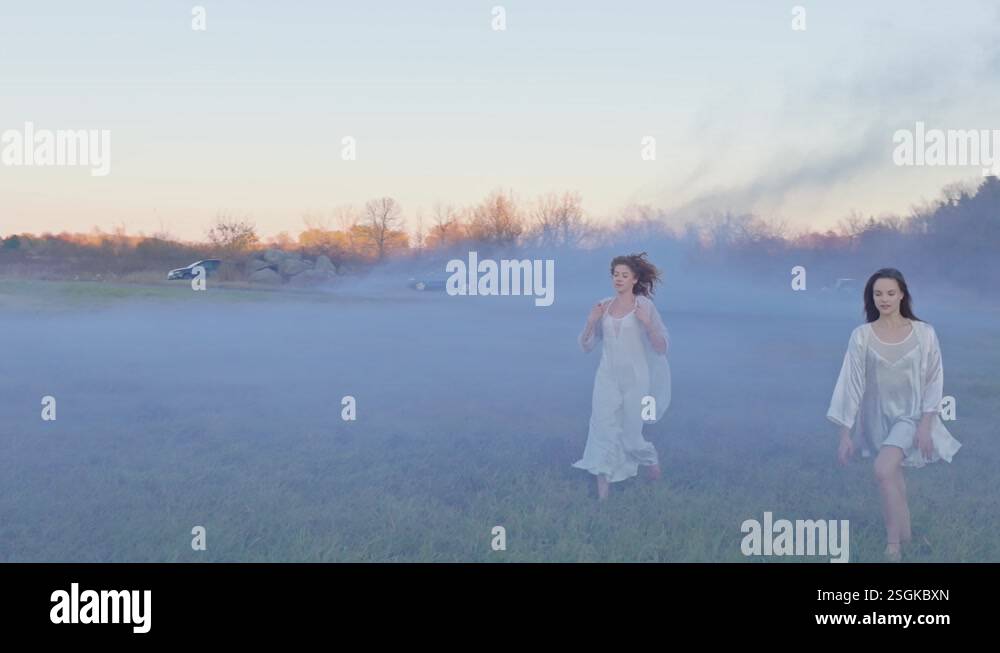 Two Happy women running in a field with fog running along side of ...