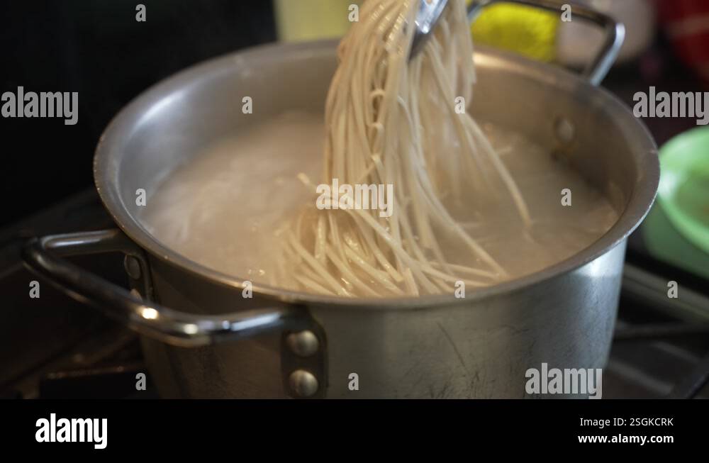 Chef Tossing Pasta Noodles In A Pot Of Boiling Water Using Tongs. Slow ...