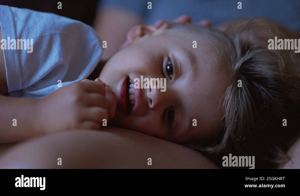 Mother caresses child blond hair. Little boy laying on mom leg ...