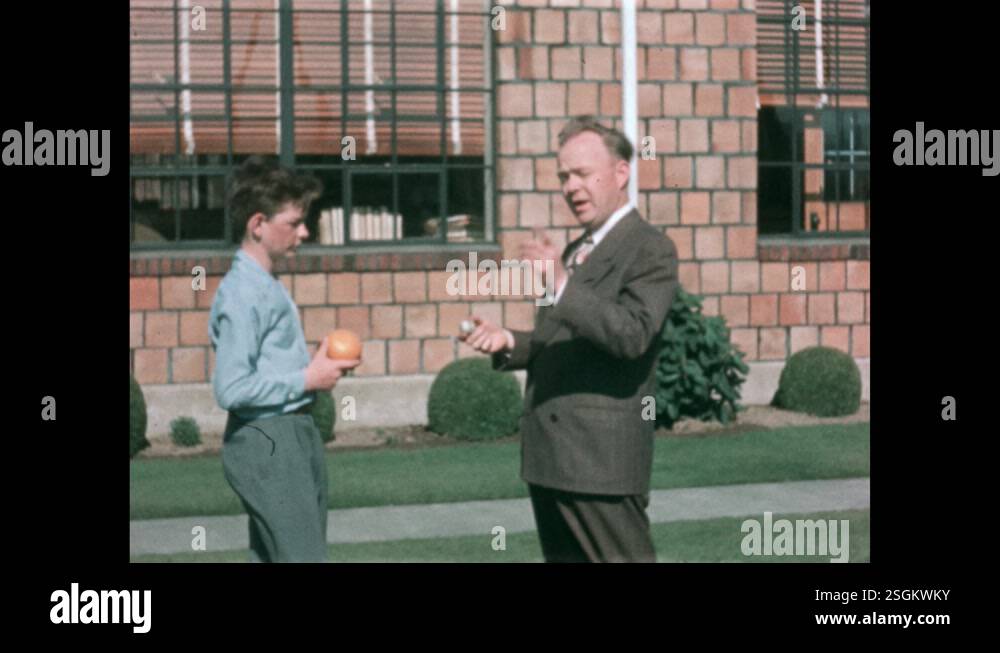 1950s: Film slate. Man and boy, man holds orange attached to string ...
