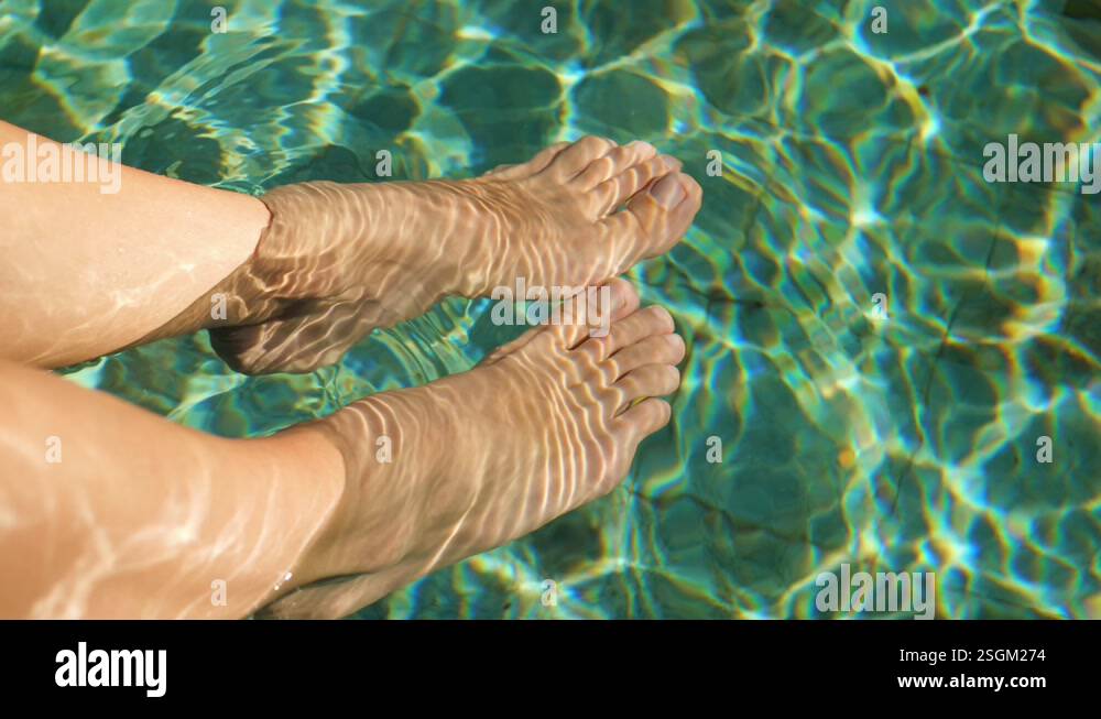 Beautiful female ankle-deep feet in clear sea water. Water heated by ...