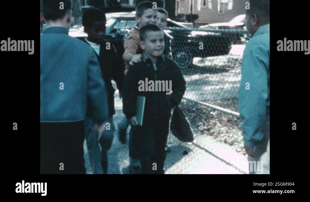 1970s: Boy greets classmates in front of school. Girls hold hands and ...
