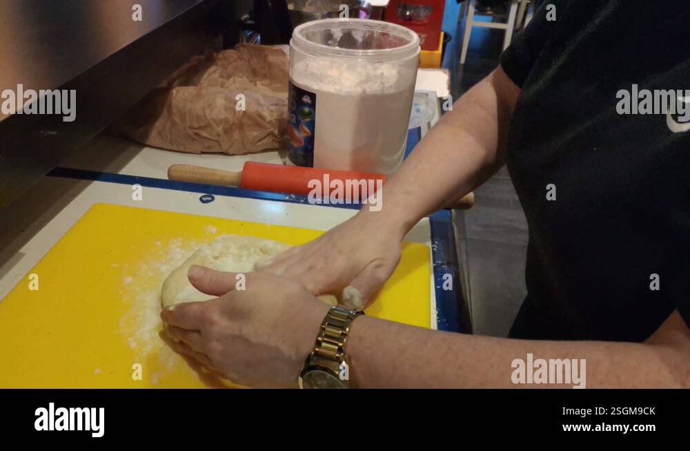 the hands of the worker with golden clock kneading dough with wheat ...