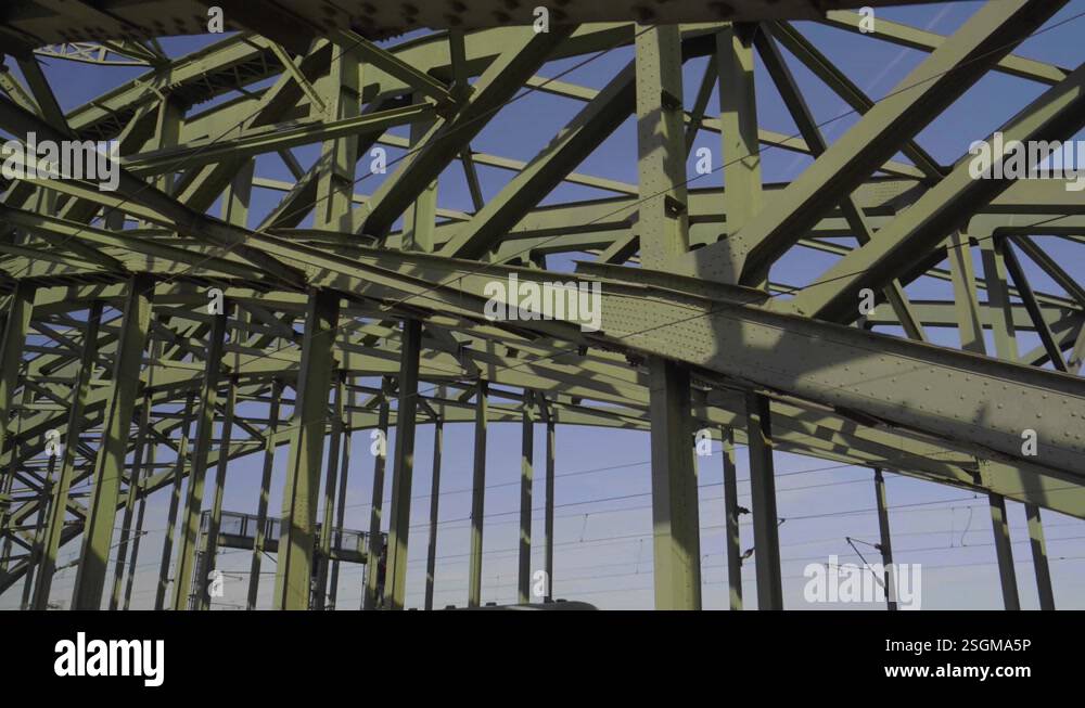 Truck left reveal shot of a commuter train from behind the steel beam ...