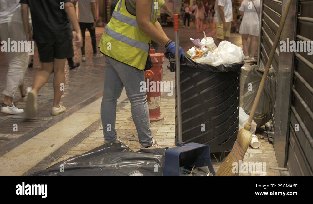 Female street cleaner emptying overflowing waste bin Stock Video ...