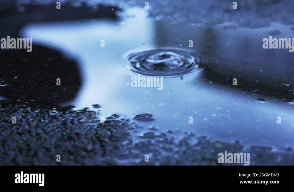 Single big water drop falling in a puddle on the concrete. Slowmotion ...