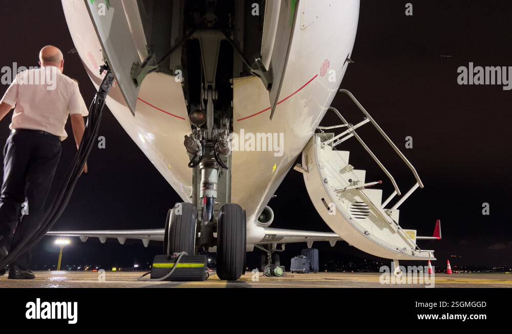 Pilot doind the external walk-around to a modern jet during a stopover ...