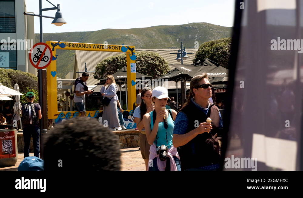Tourists taking travel pictures in the yellow Hermanus Waterfront frame ...