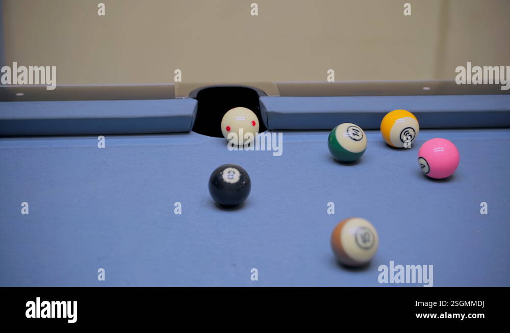 Cue ball hitting many pool balls near table hole on a blue baize ...