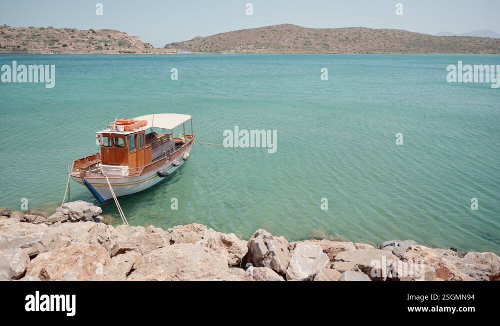 Single fishing boat tide to a rock floating peacefully in Greek island ...