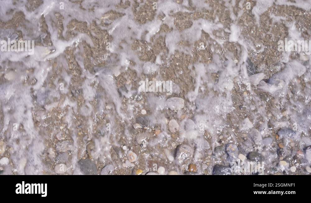 Close up sea water wash into the beach and shore flowing over rocks and ...
