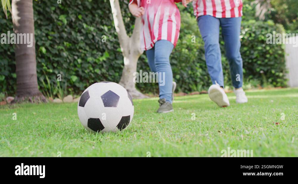 Video of low section of biracial mother and daughter playing soccer in ...
