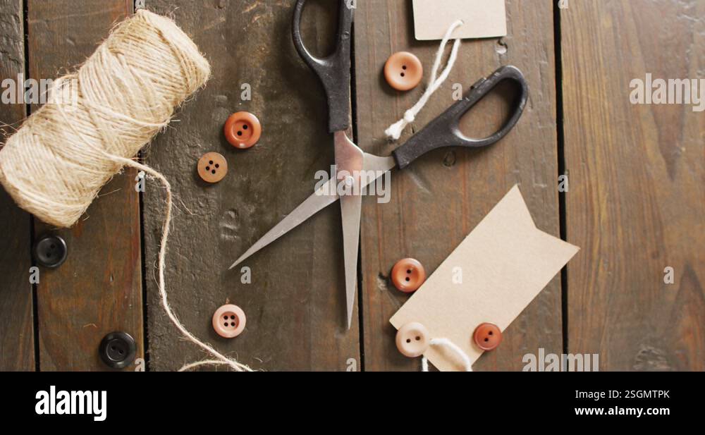 Video of scissors, twine string, buttons and gift tags on dark wood ...