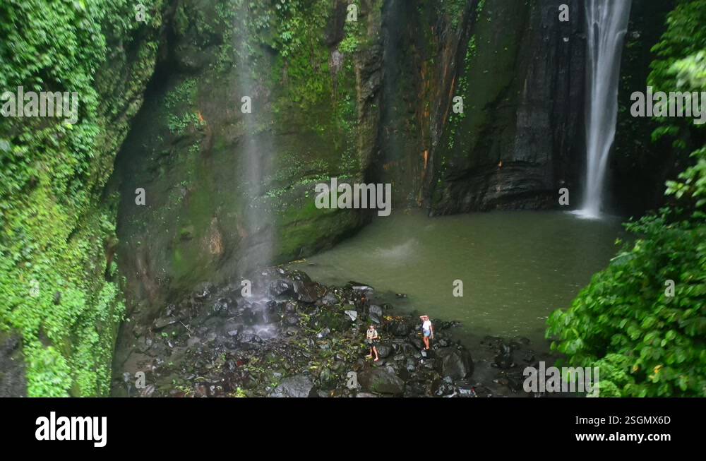 aerial zoom out of Sekumpul waterfall and lagoon with tourists in ...