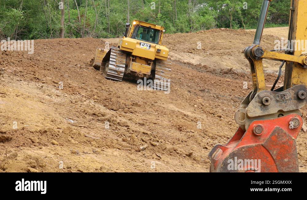 Large and powerful Caterpillar bulldozer working on a slope to form the ...