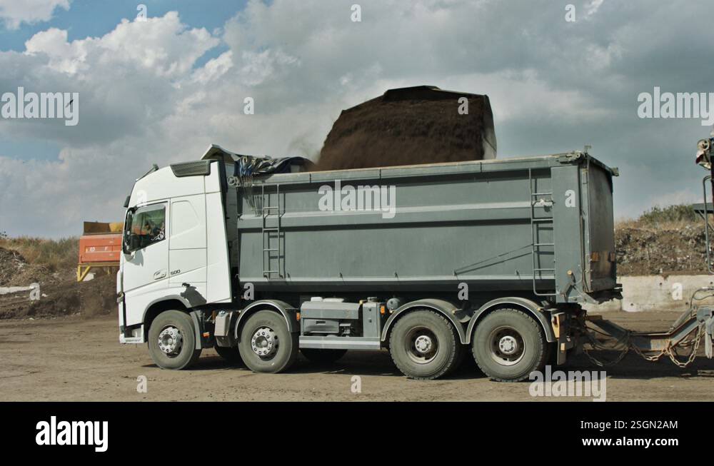 Industrial compost production site. Tractors loading compost into ...