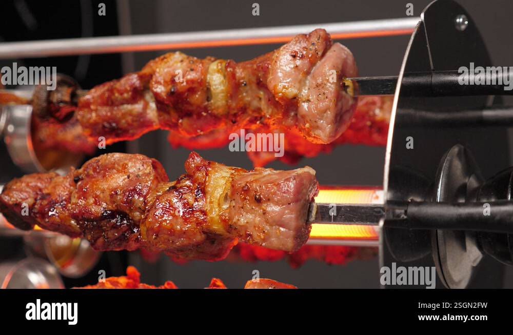 Cooking pork kebab in electrical barbecue. Rotating meat on skewers ...