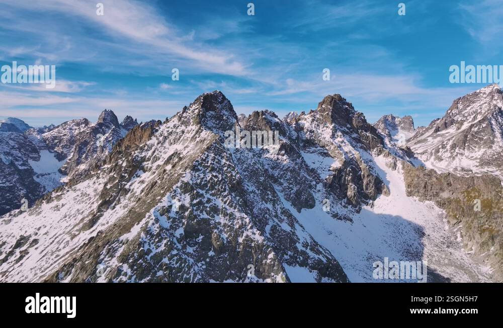 Close flight approach to the snow-capped peaks of the rocky mountain ...