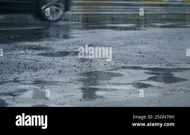 Raindrops create ripples as puddles form on the pavement Stock Video ...