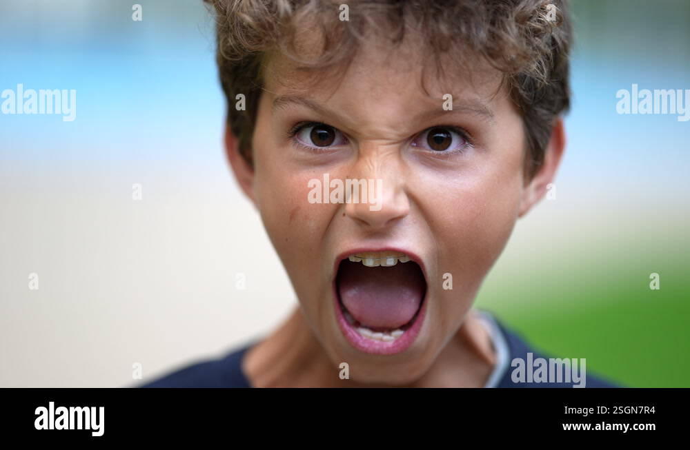One angry young boy screaming to camera. Preteen child open mouth ...