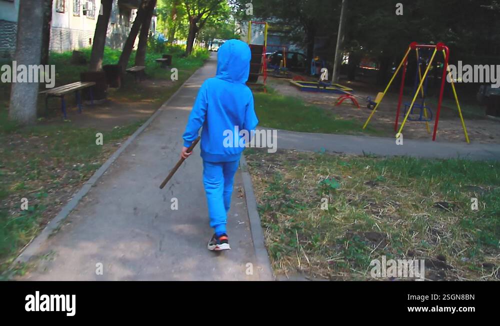 Angry child with stick walks on playground in tracksuit Stock Video ...