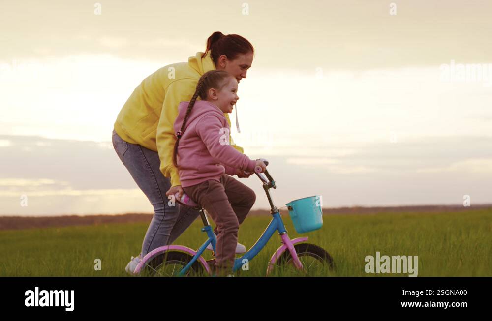 mother teaches ride bike little daughter child sunset. happy family ...