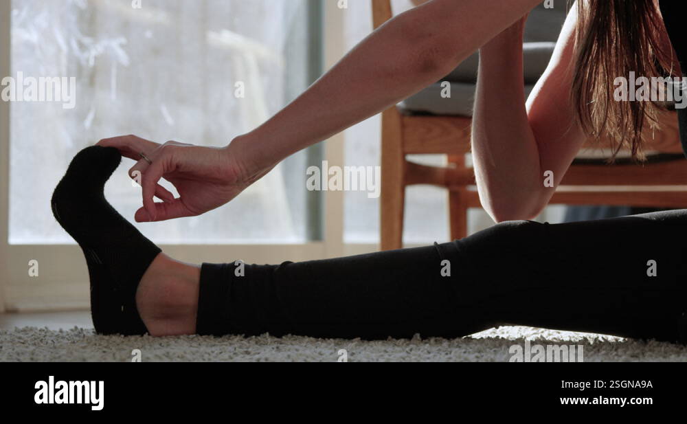 Fit woman stretches leg - close up on hand pulling on toes - side ...