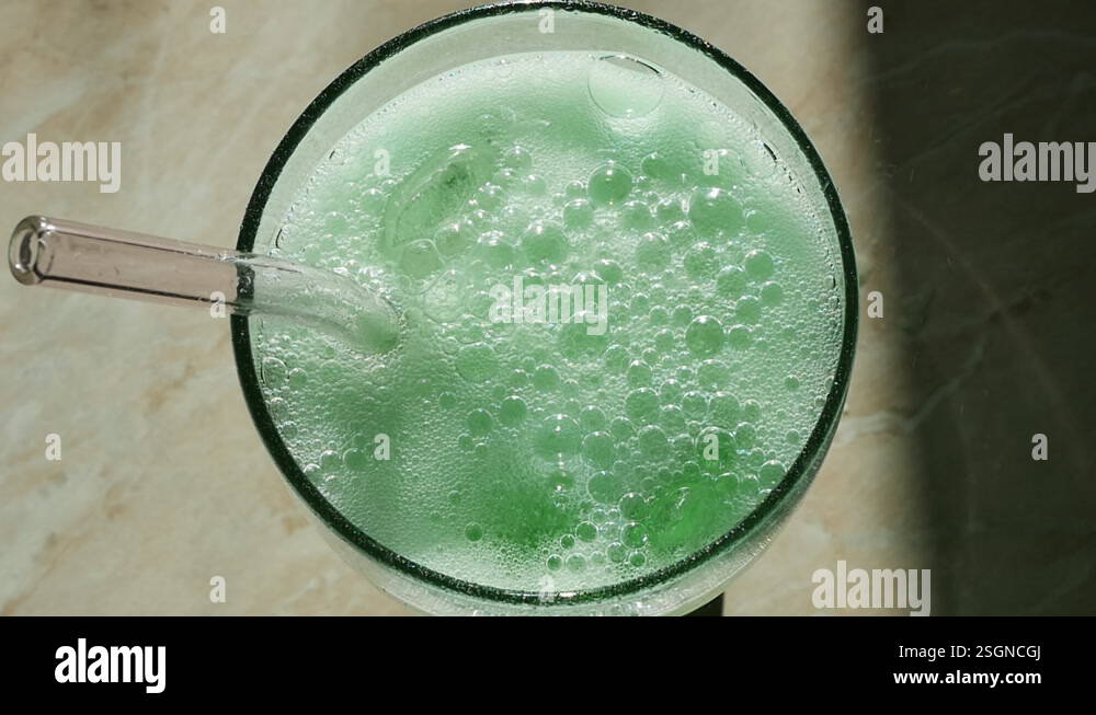 Top view pouring a fizzy drink into a glass with pieces of ice and a ...