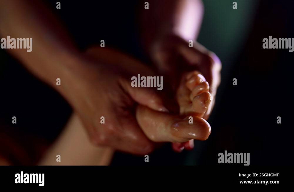 Close-up of the masseur hands massaging the feet and toes of a young ...