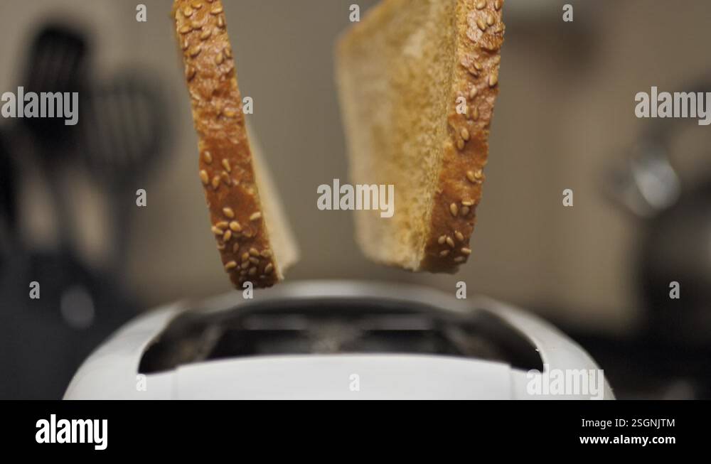 Close-up of sliced fried white bread flying out of an electric toaster ...