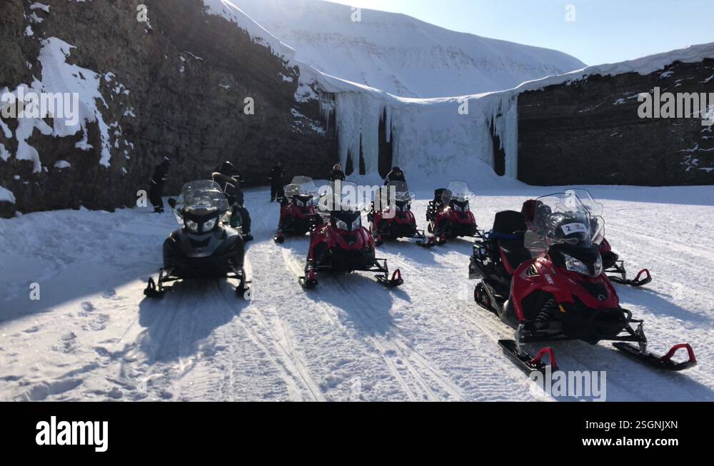 snowmobile explorers in front of frozen waterfall in Svalbard Arctic ...