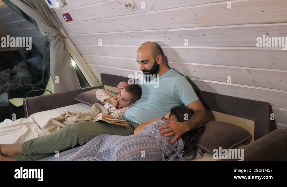 Caring father reading bedtime story to his children at home. Evening ...