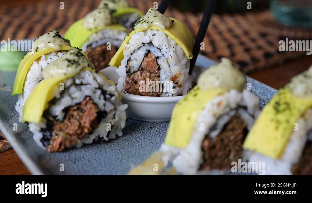Close-up of a set of Japanese sushi. The man holds wooden black sticks ...