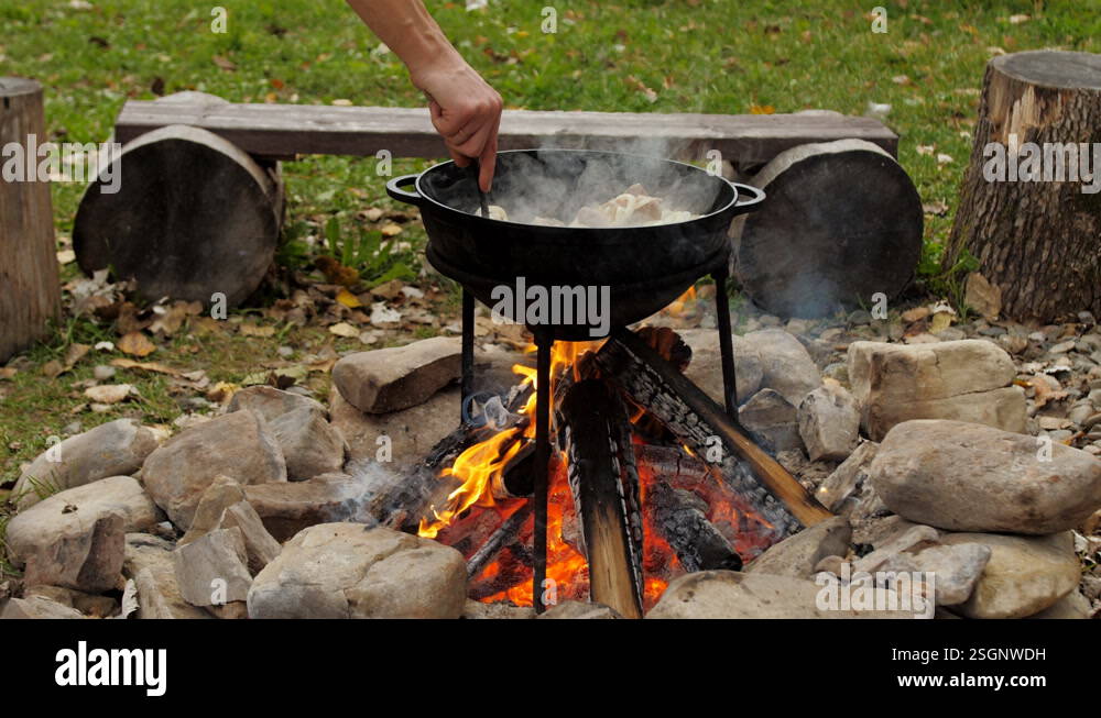 Cooking over a fire in a large cast-iron cauldron during the absence of ...