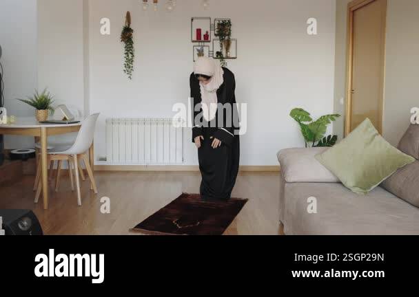 Muslim woman performs salah in slow motion in a living room setting ...