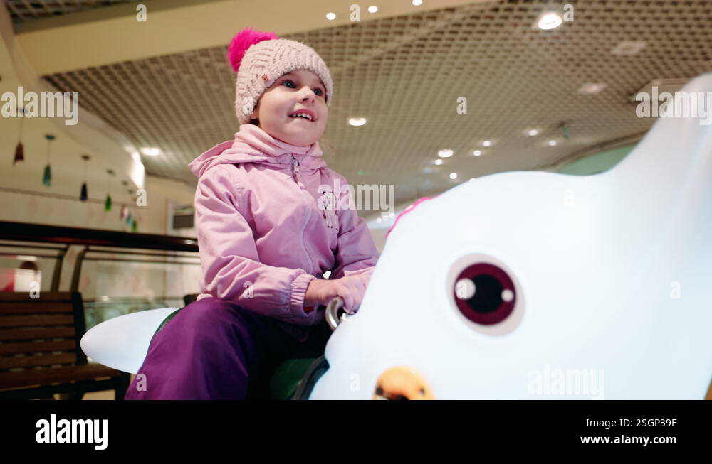 Involved cute girl is having fun on a dolphin carousel in mall Stock ...