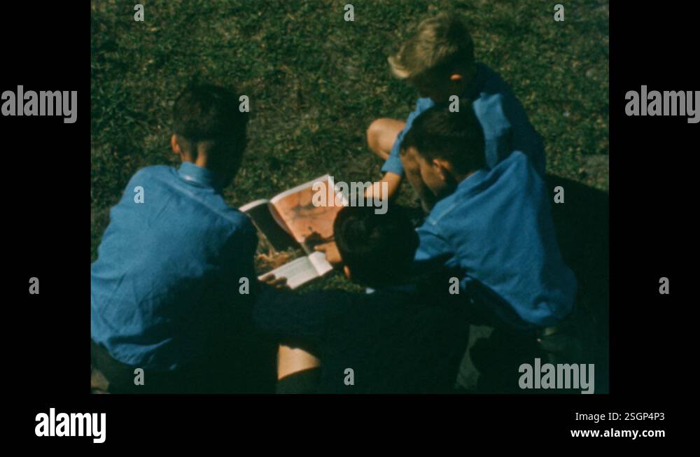 1940s: Boys sit in field reading book. Man in suit talks to classroom ...